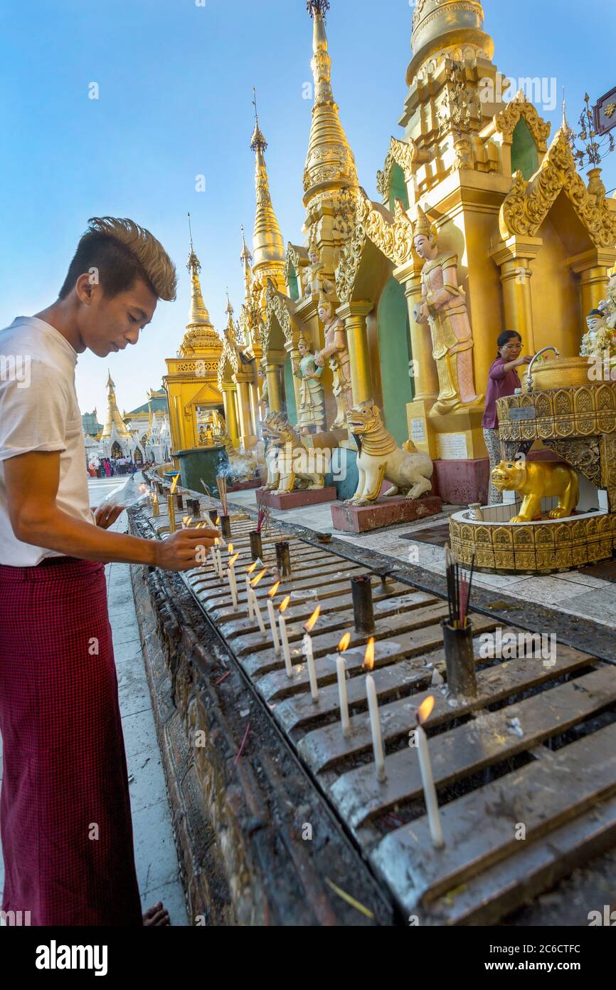 A worshipper lights a candle at a shrine in the Shwedagon Pagoda in ...