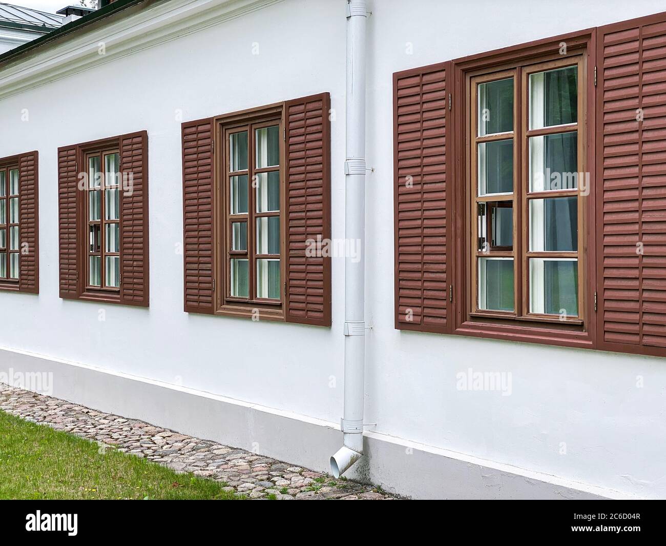 row of classical wooden windows with shutters on white building facade ...