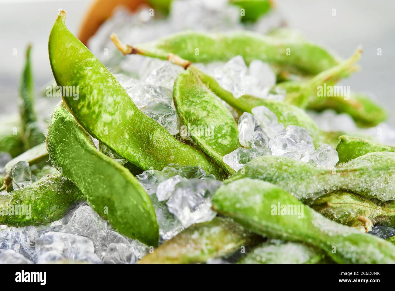 Frozen Edamame or soybeans in the mix with crushed ice on a blue ...