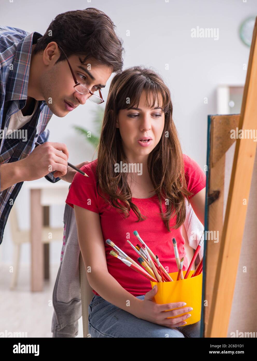 The artist coaching student in painting class in studio Stock Photo - Alamy