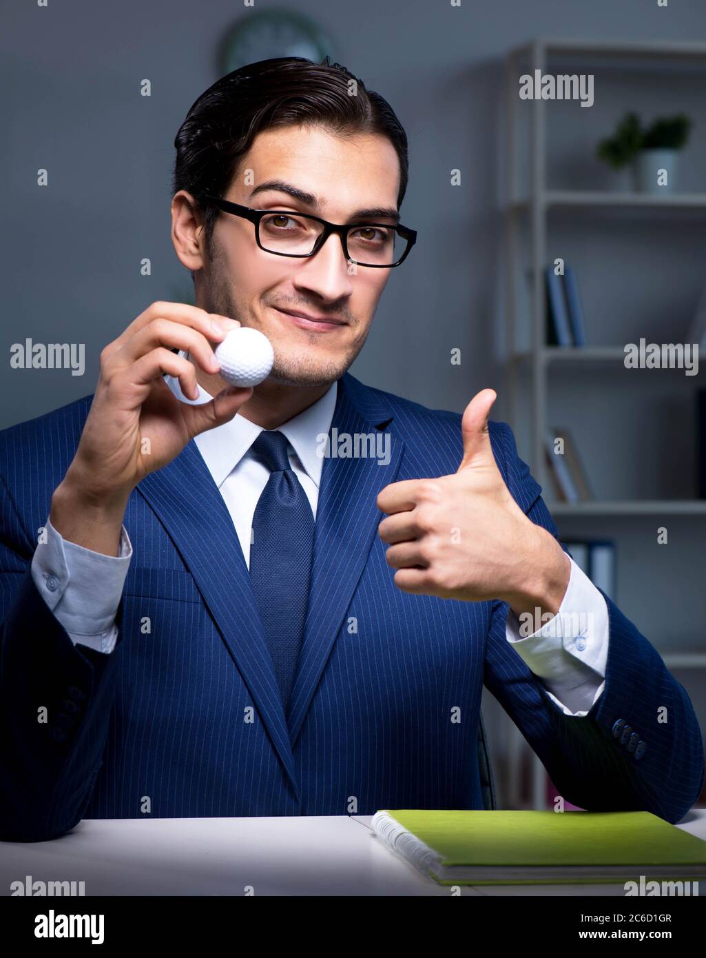 The young employee with golf ball in office Stock Photo - Alamy