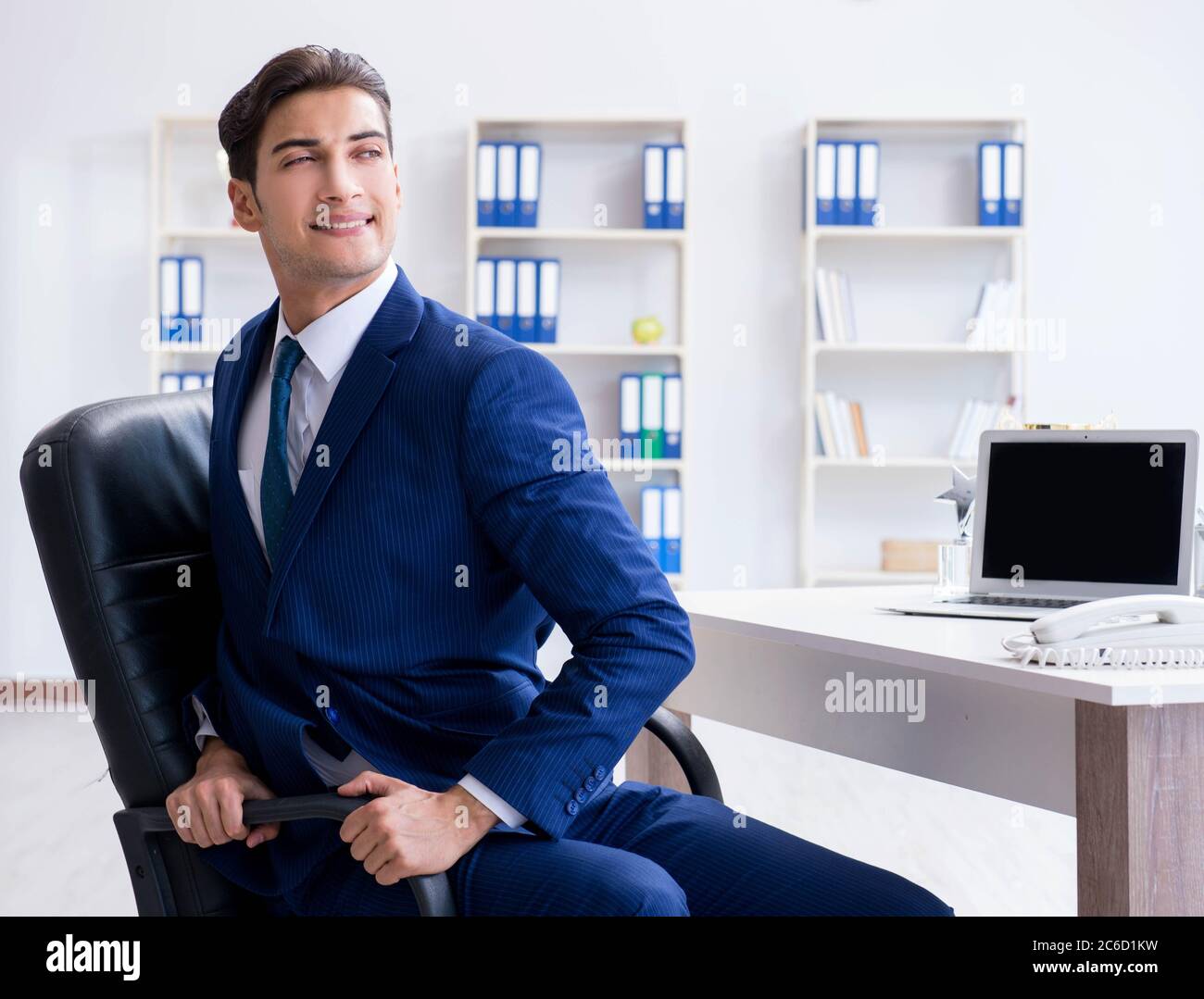 The young businessman doing sports stretching at workplace Stock Photo ...