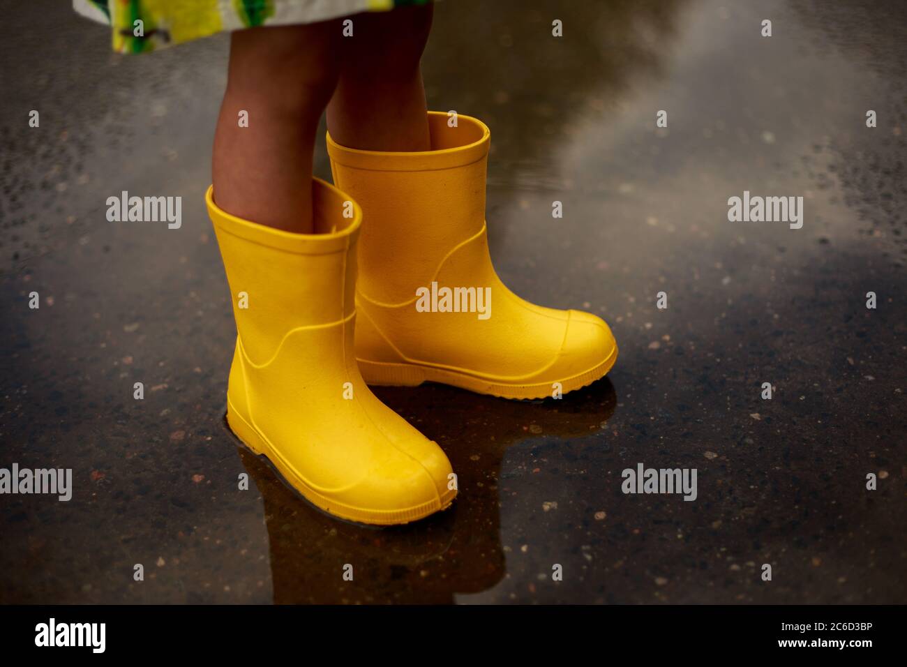 Little blond girl in a yellow boots in the puddle Stock Photo - Alamy