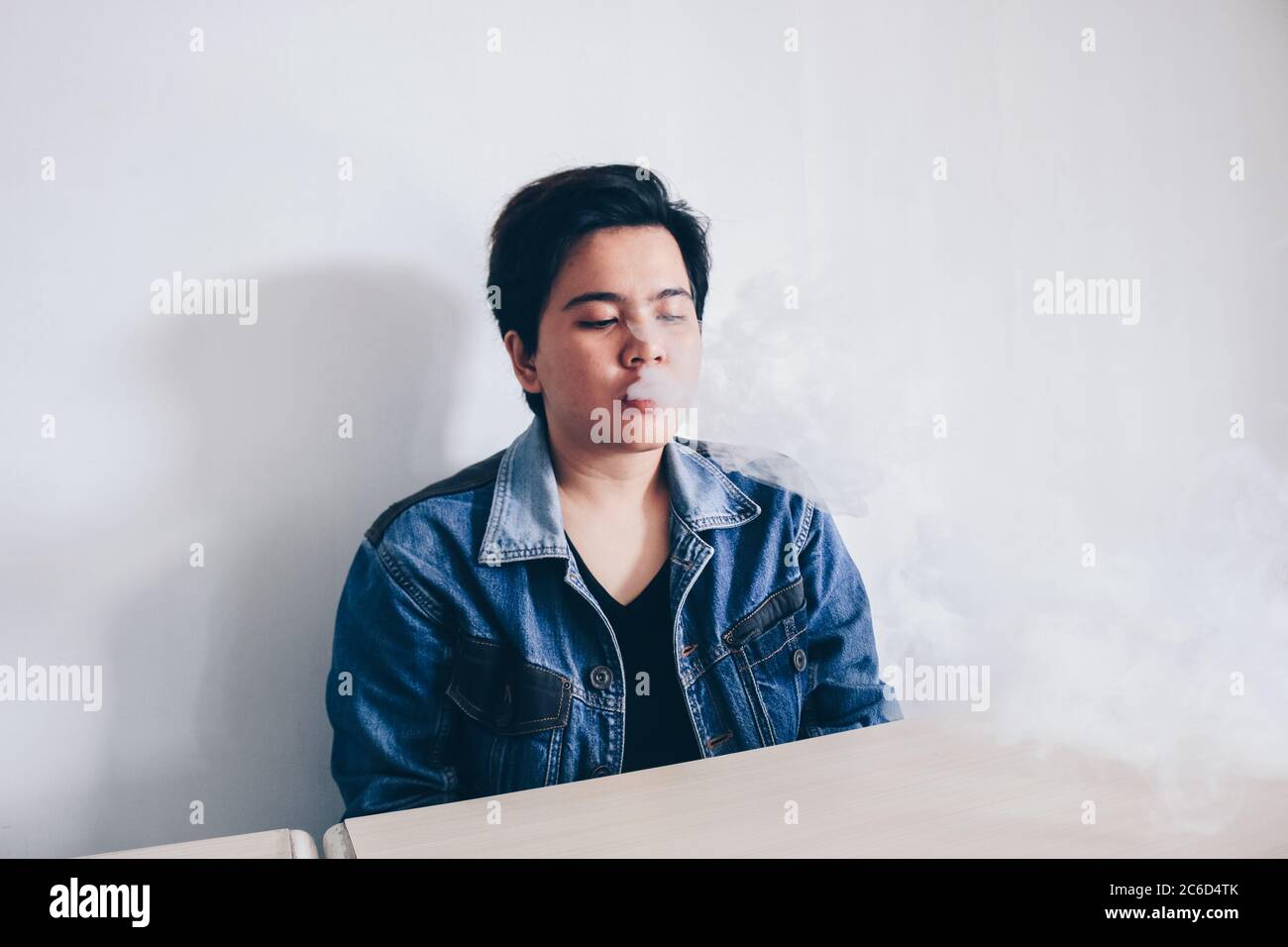 Asian beautiful short hair girl wear jeans jacket is smoking electronic ...