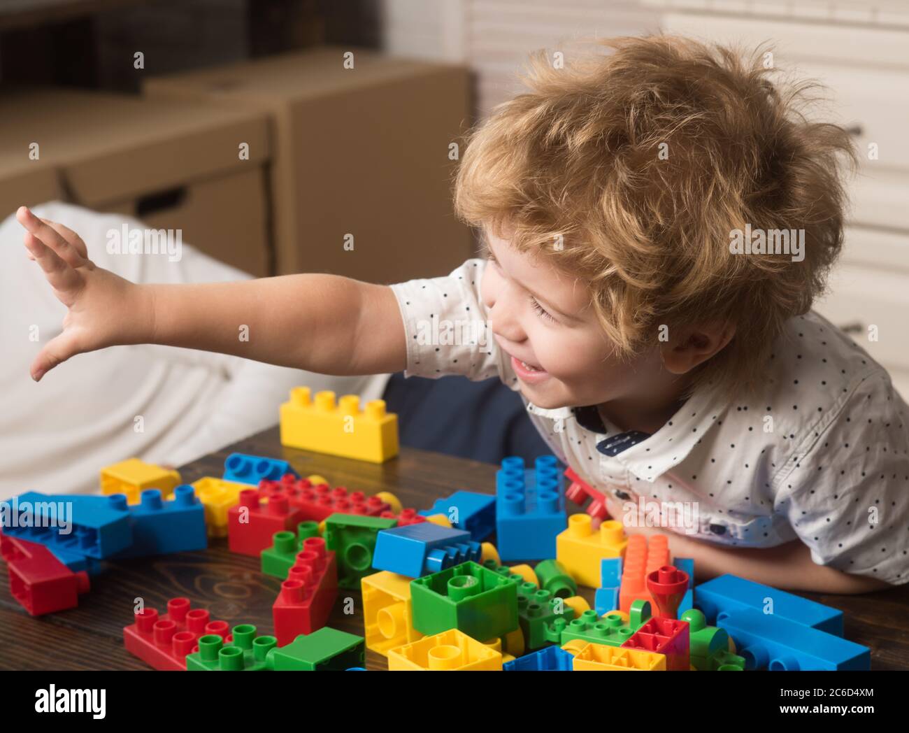 Kid with smiling face near colorful plastic bricks. Boy in playroom on ...