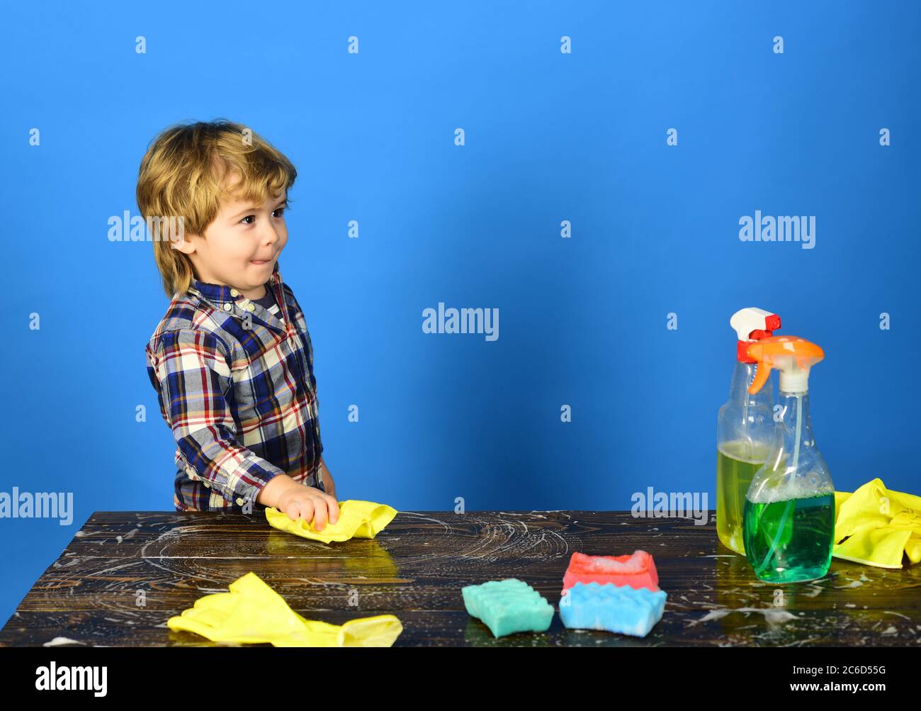 Boy in checkered shirt on blue background. Kid with smile cleaning ...