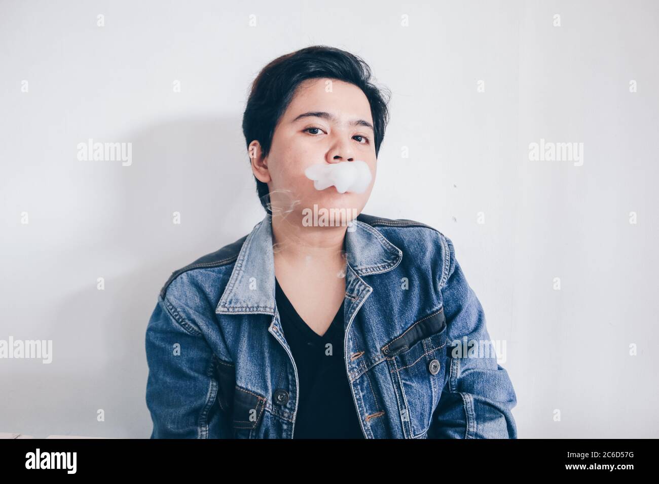 Asian beautiful short hair girl wear jeans jacket is smoking electronic ...