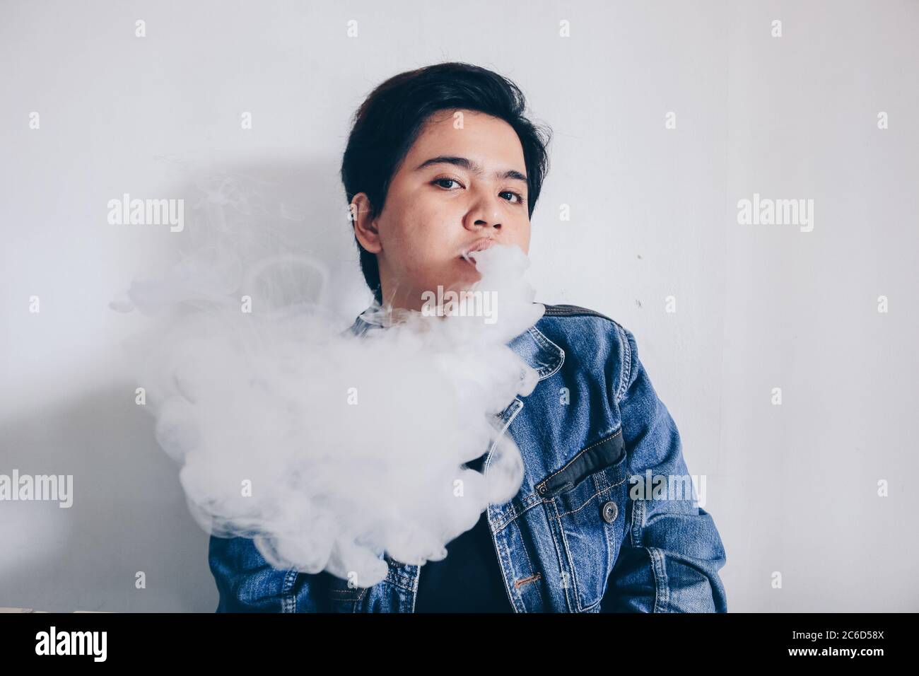 Asian beautiful short hair girl wear jeans jacket is smoking electronic ...