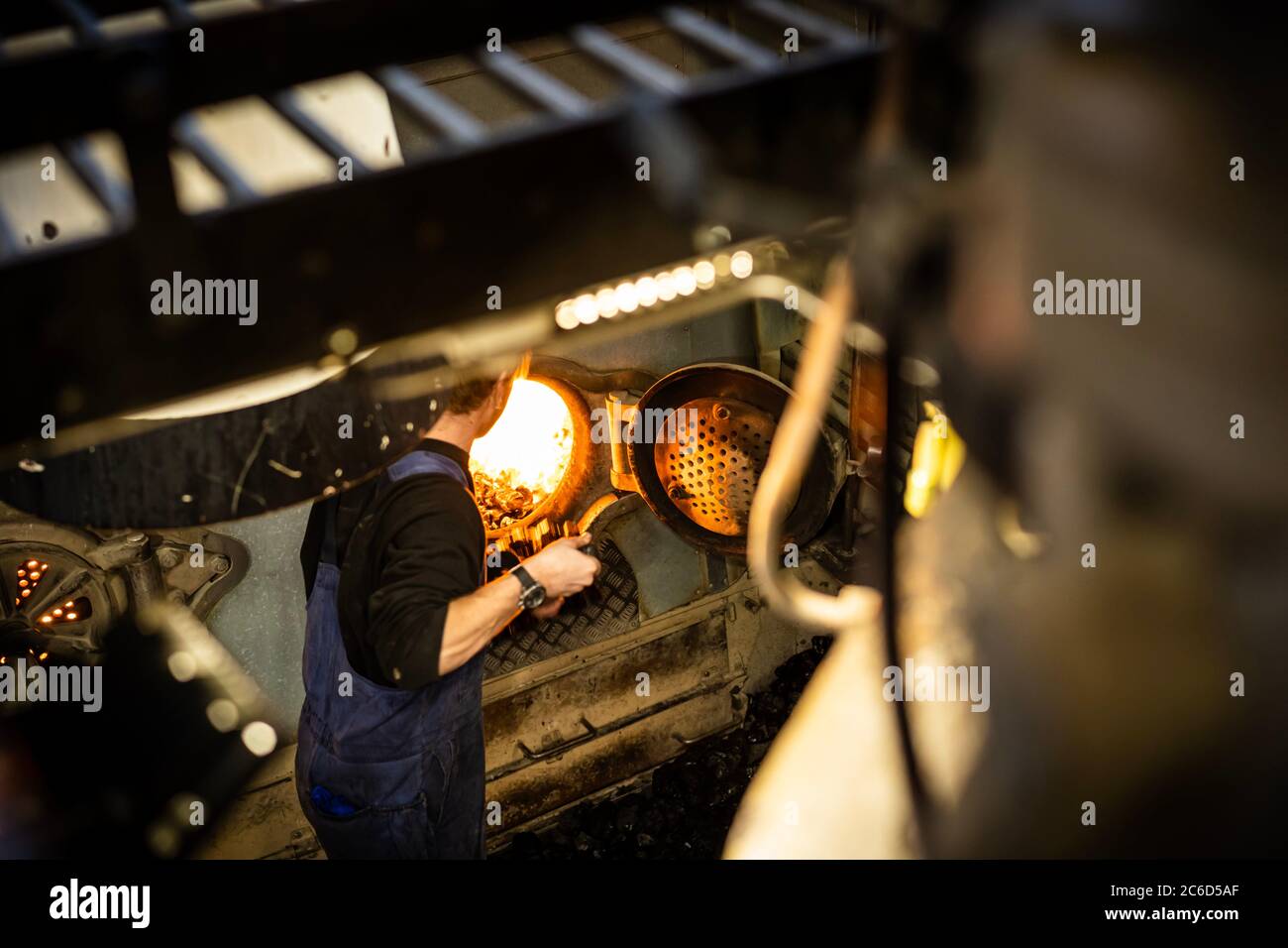A worker insert a coal inside the engine of coaled power steam ship ...
