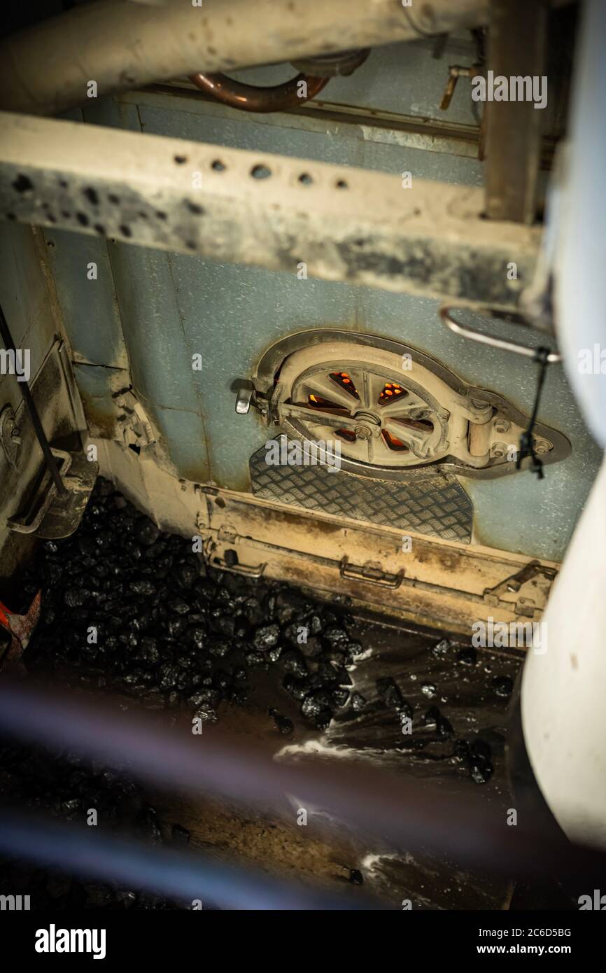 A worker insert a coal inside the engine of coaled power steam ship ...