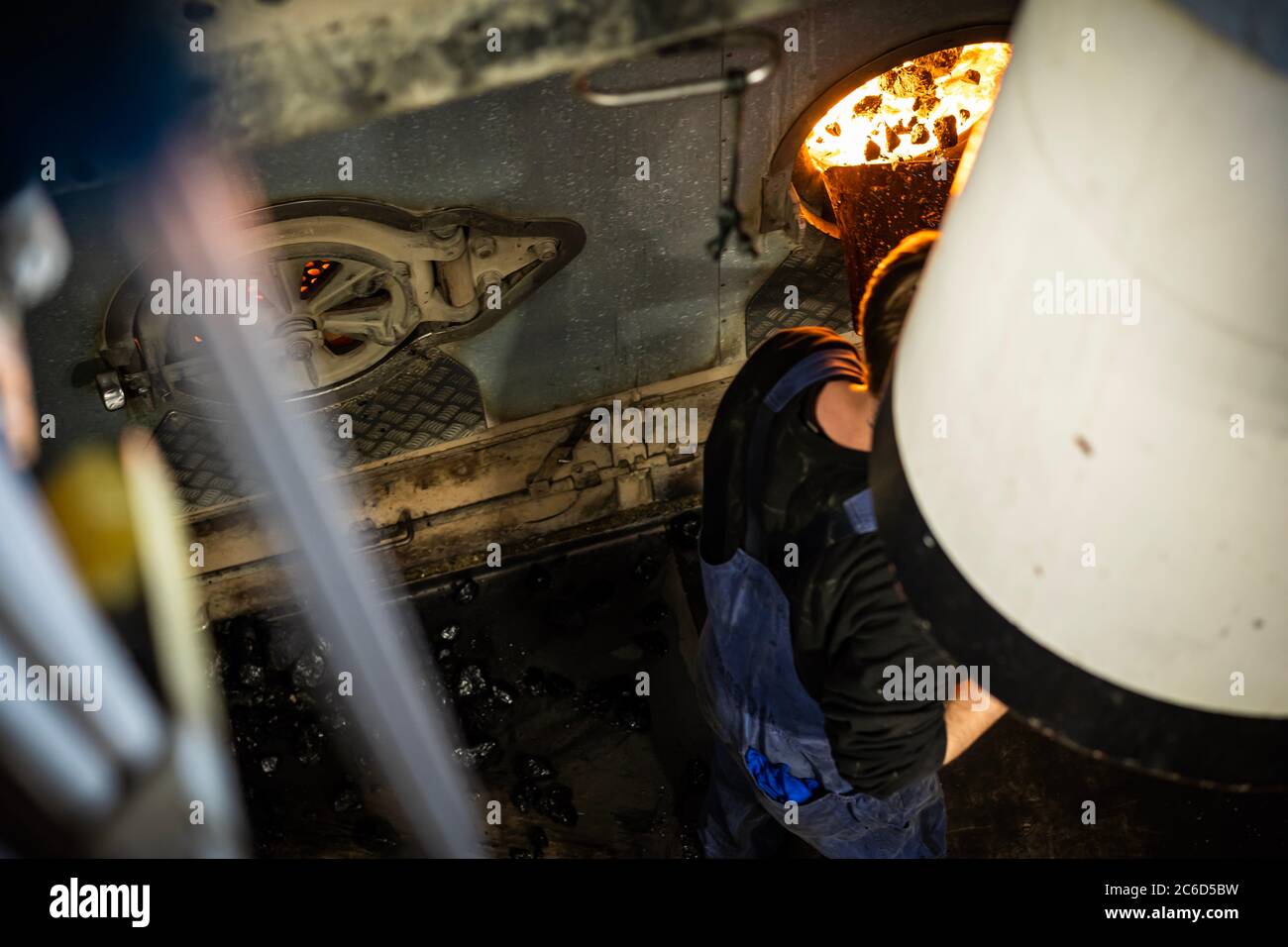 A worker insert a coal inside the engine of coaled power steam ship ...