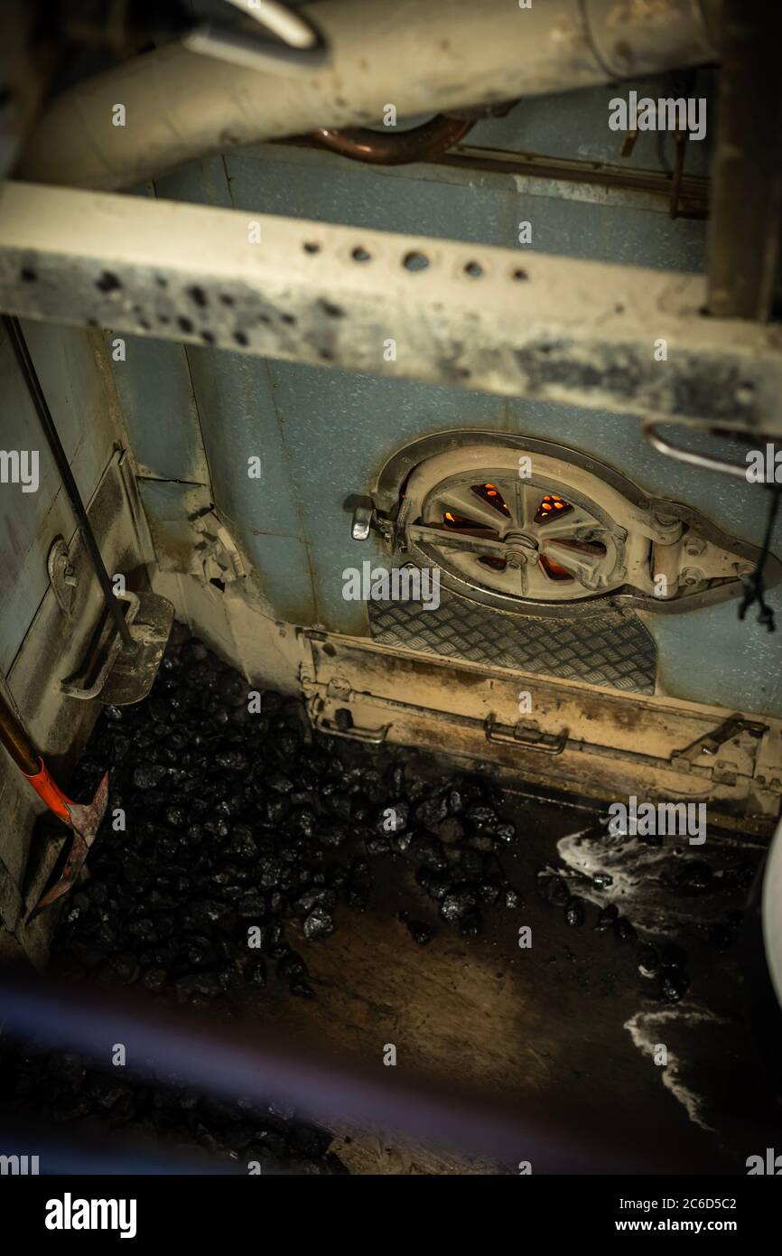 A worker insert a coal inside the engine of coaled power steam ship ...