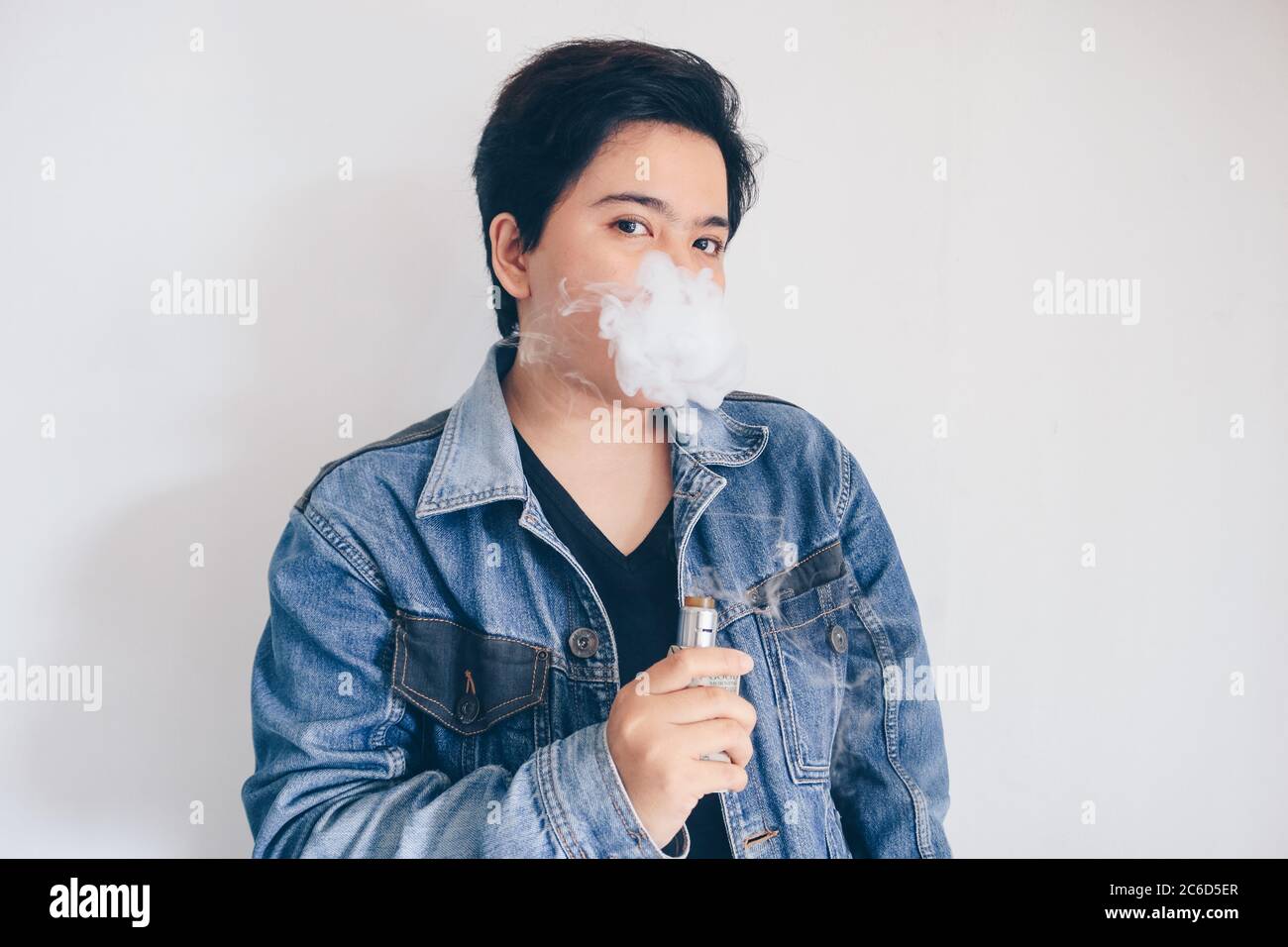 Asian beautiful short hair girl wear jeans jacket is smoking electronic ...