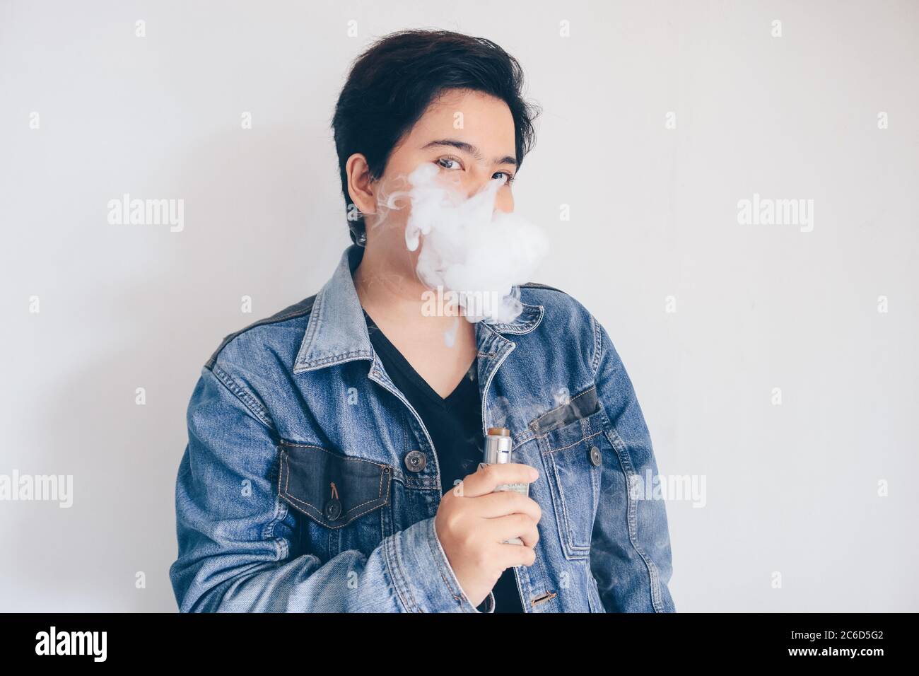 Asian beautiful short hair girl wear jeans jacket is smoking electronic ...