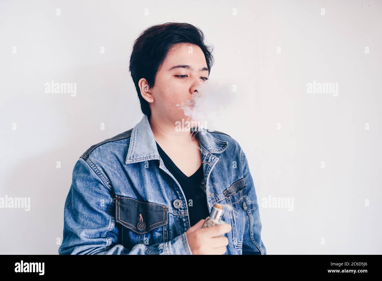 Asian beautiful short hair girl wear jeans jacket is smoking electronic ...