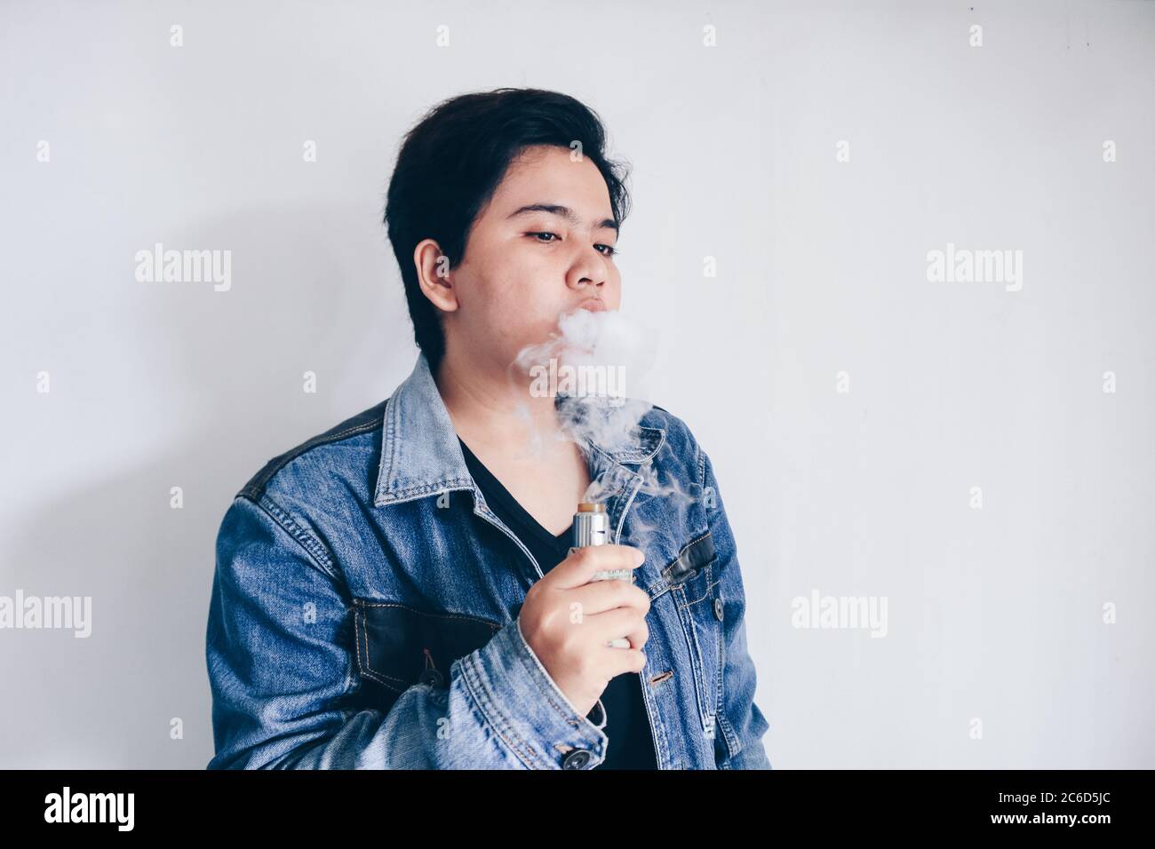 Asian beautiful short hair girl wear jeans jacket is smoking electronic ...