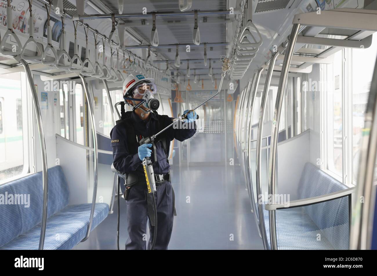 A worker sprays anti-virus liquid on a Tokyo Metro train car on July 9 ...