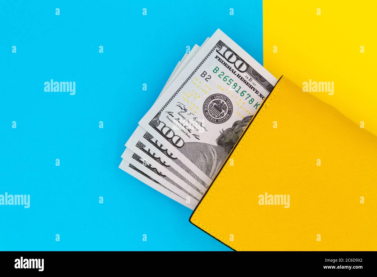 Close-up of yellow wallet with 100 dollar banknotes on a colored ...