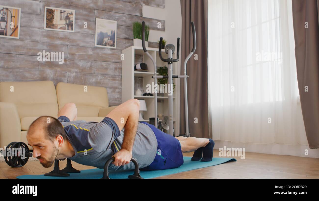 Athletic man training chest muscle doing push ups at home on yoga mat ...