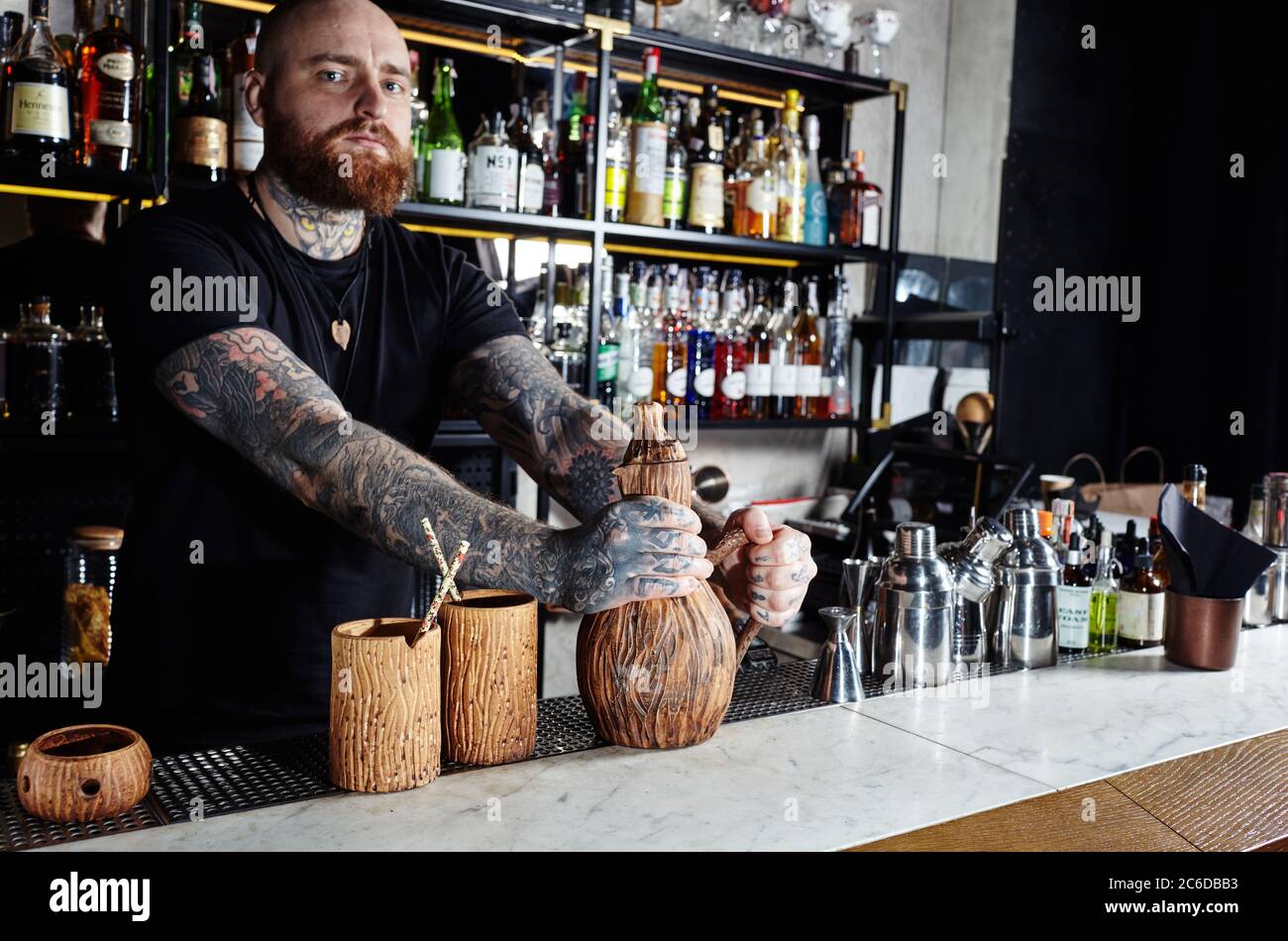 A male bartender making a cocktail on the bar counter. Clay jug with alcohol beverage.Process of ...