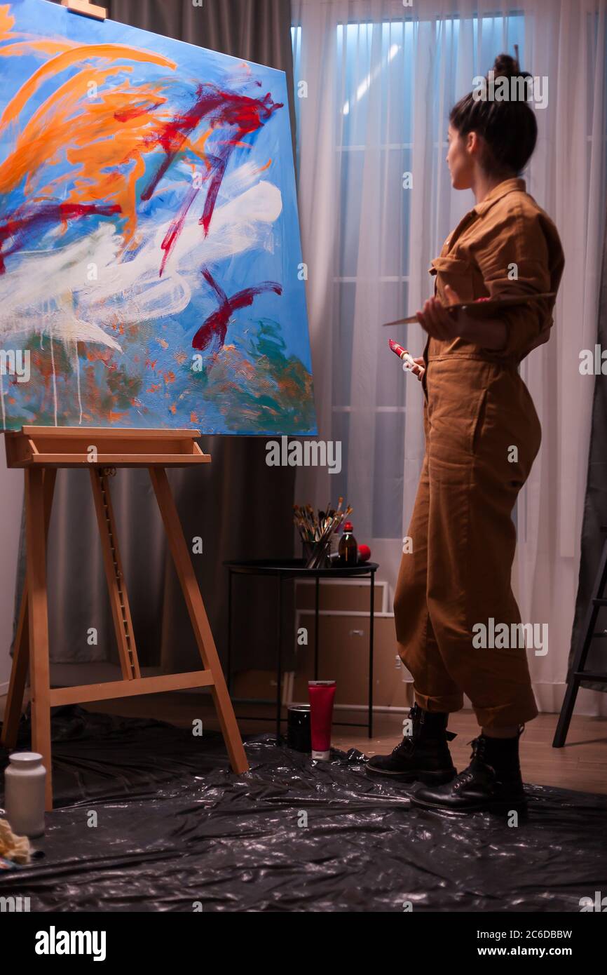 Artist admiring painting on large canvas after finishing it. Modern ...