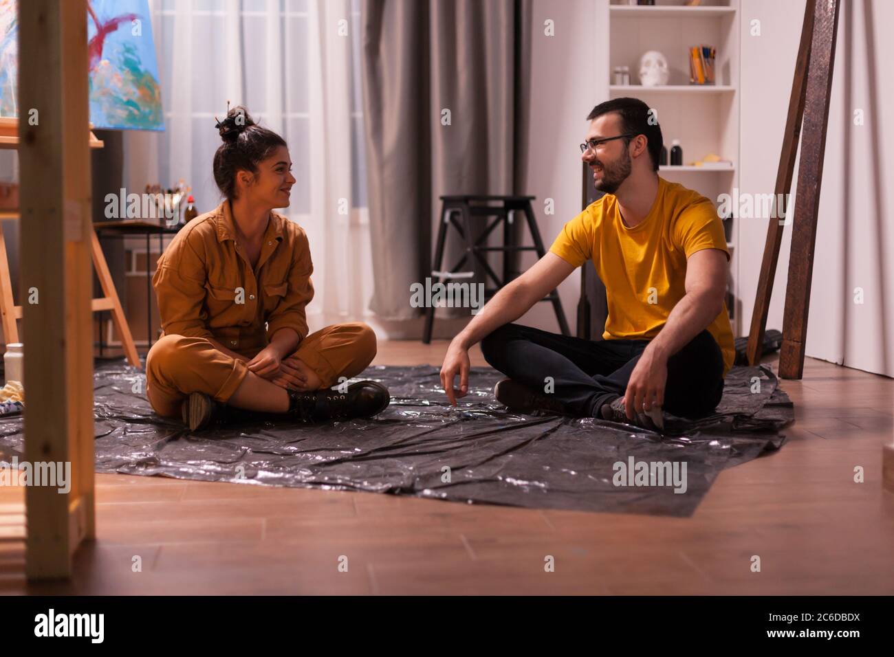 Artist having a conversation sitting on art workshop floor. Modern ...