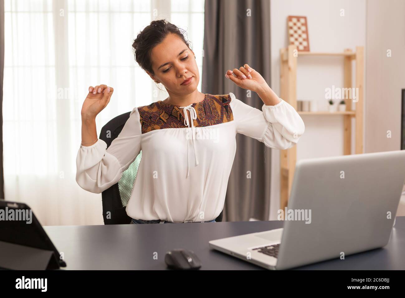 Freelancer with sore back while working on laptop from home office ...