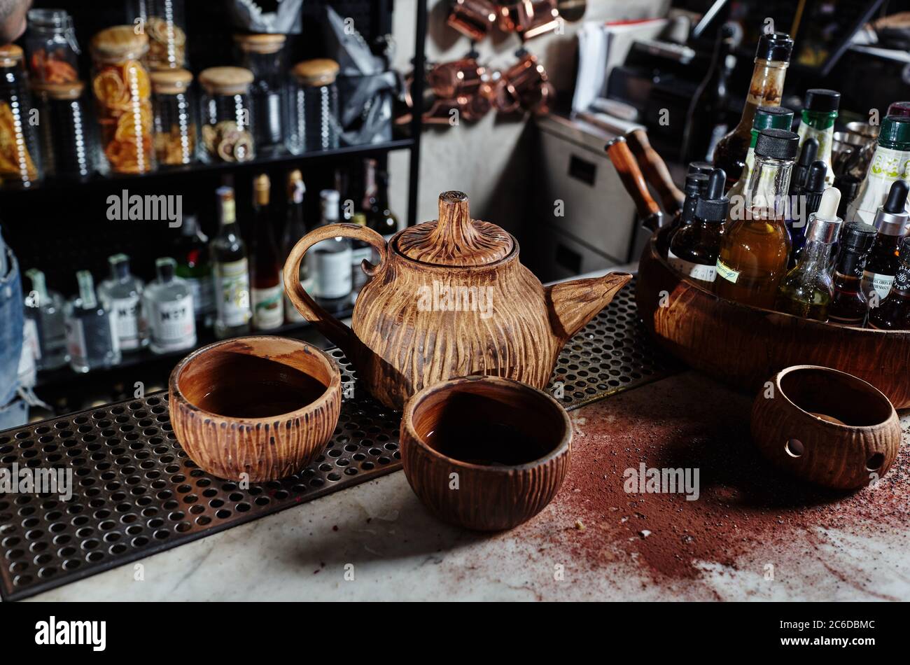 Clay teapot and ceramic cups on bar counter. Ingredients for cocktails ...