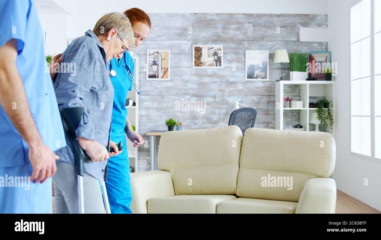Nurse team helping old disabled lady to walk in the nursing home room ...