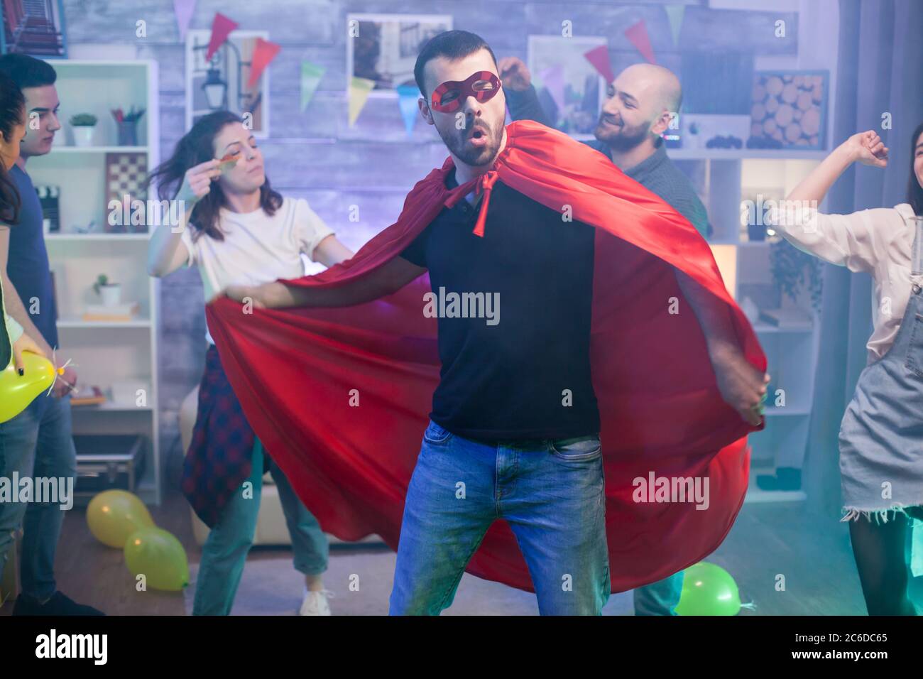 Man in red cape of superhero dancing with his friends Stock Photo - Alamy