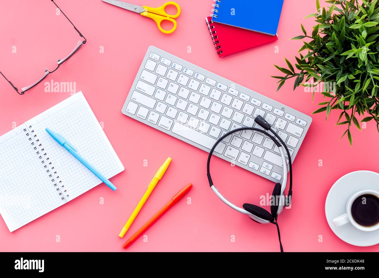 E-learning. Stationery, headphones and keyboard on pink table top-down ...