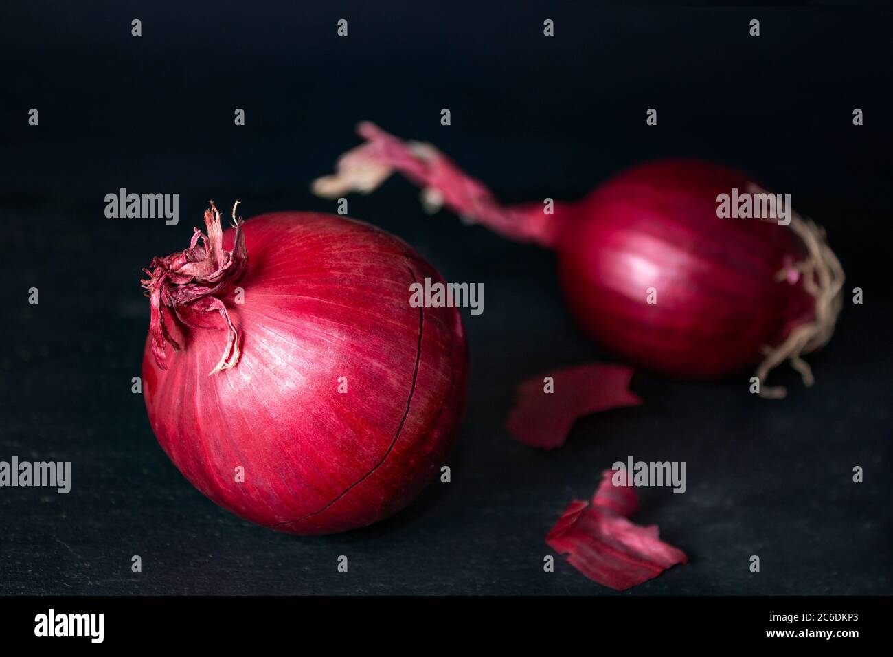 Close-up two fresh purple onions on black slate background.Horizontal ...