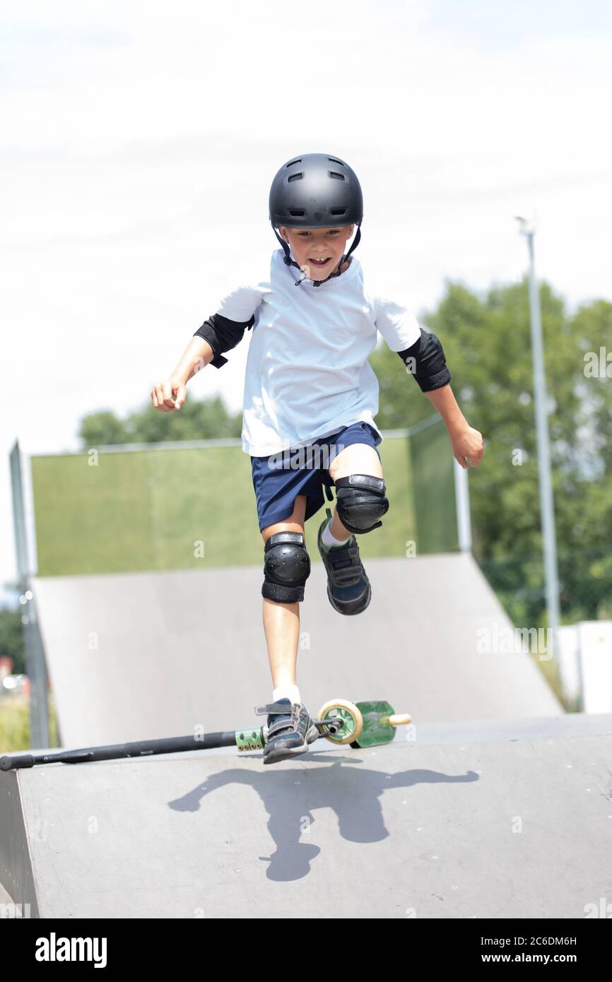 Fall while jumping. A cute little boy rides a scooter in a skatepark. A ...