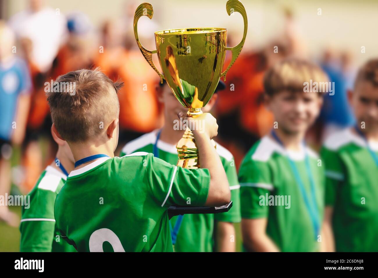 Group of young boys rising up golden trophy for winning sports school ...