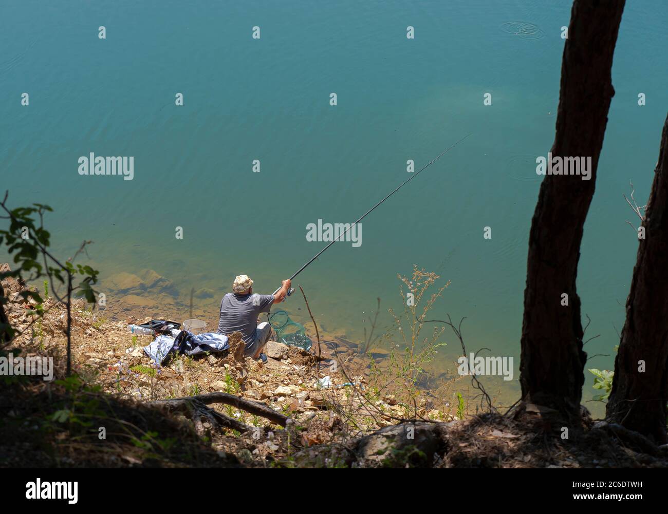fisherman fishing with cane in clear lake Stock Photo - Alamy