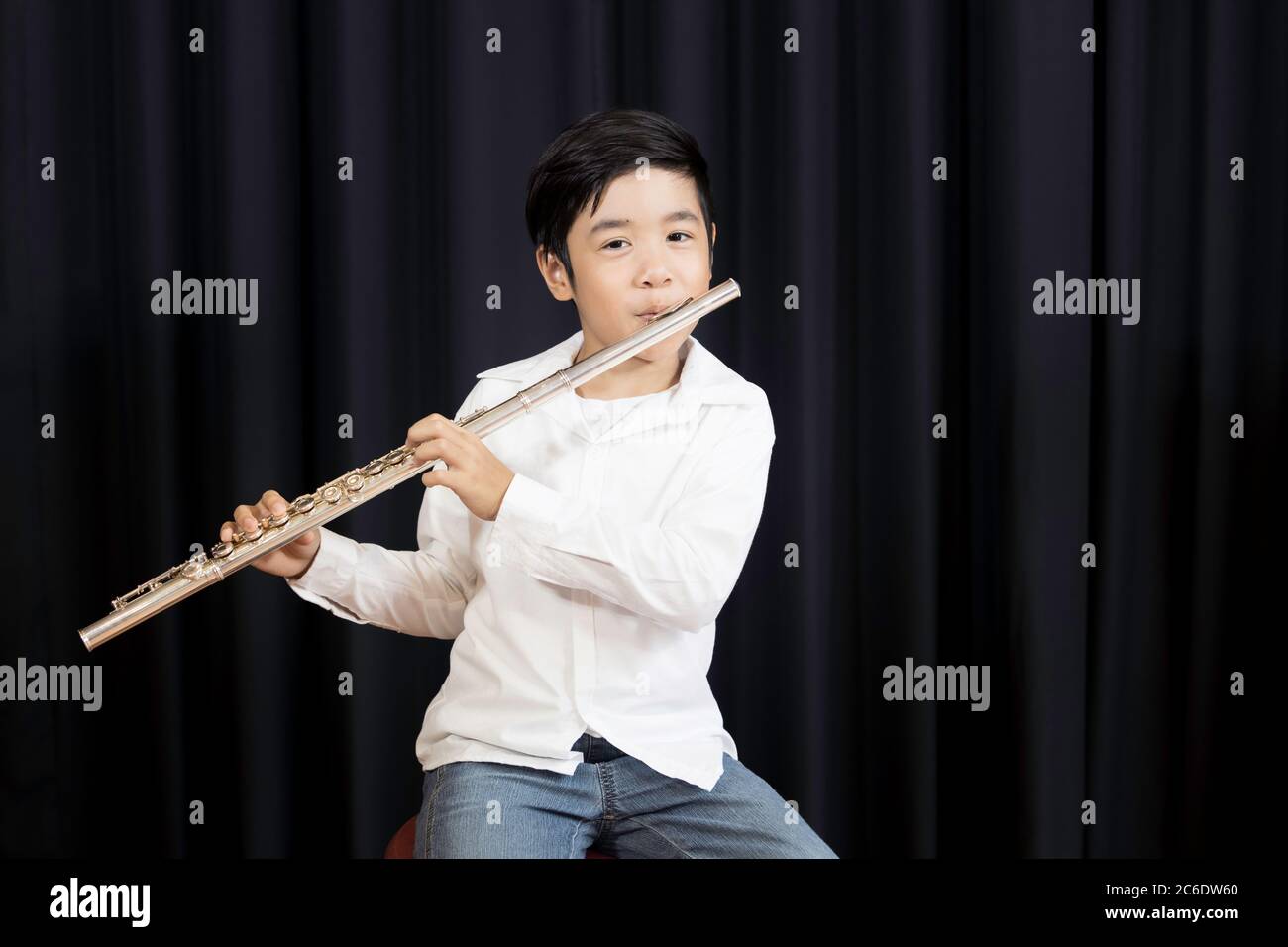 Portrait of a cute Asian elementary school boy wearing a jeans and a ...