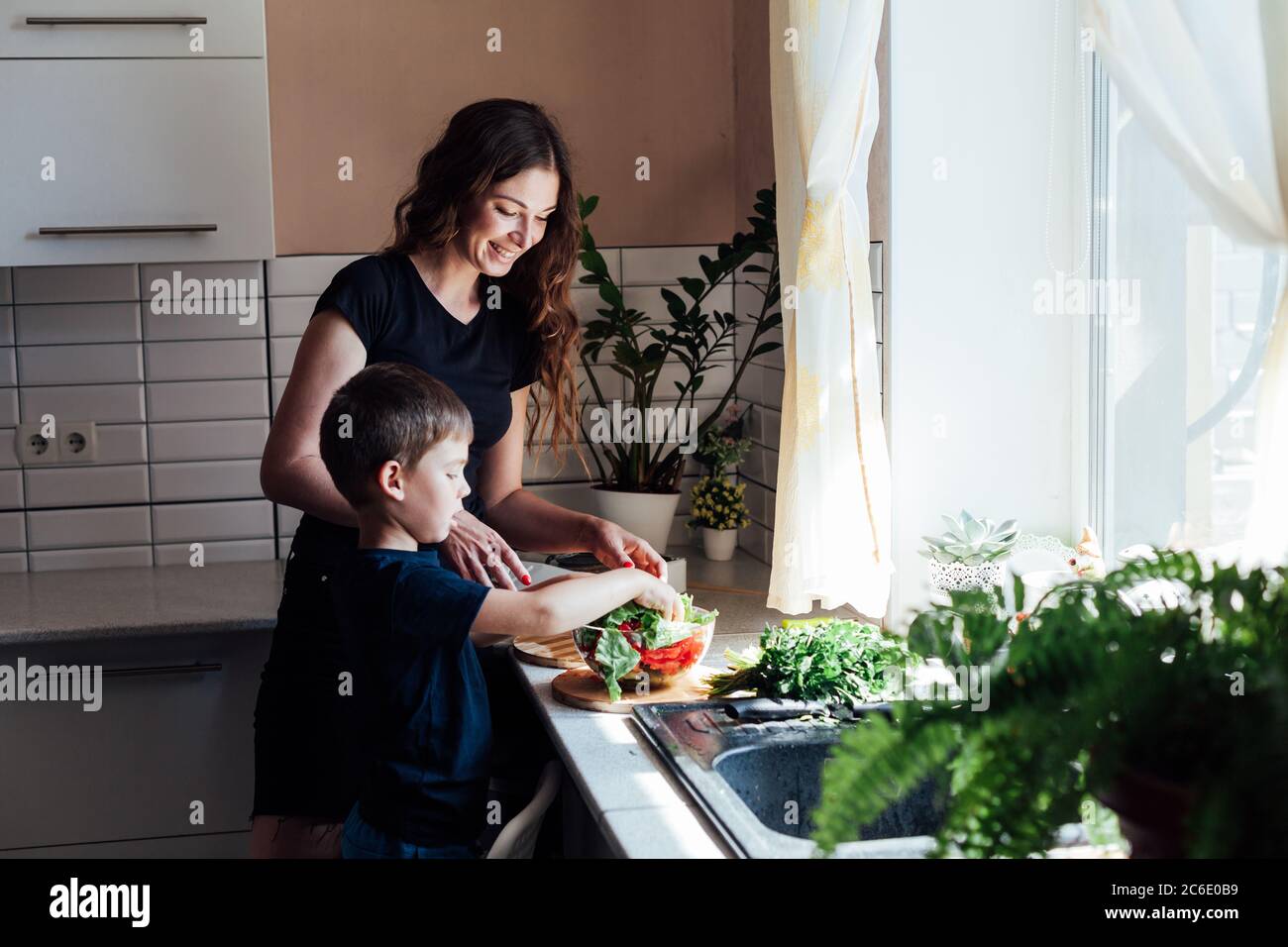 Little son helps mom cook vegetable salad in the kitchen Stock Photo ...