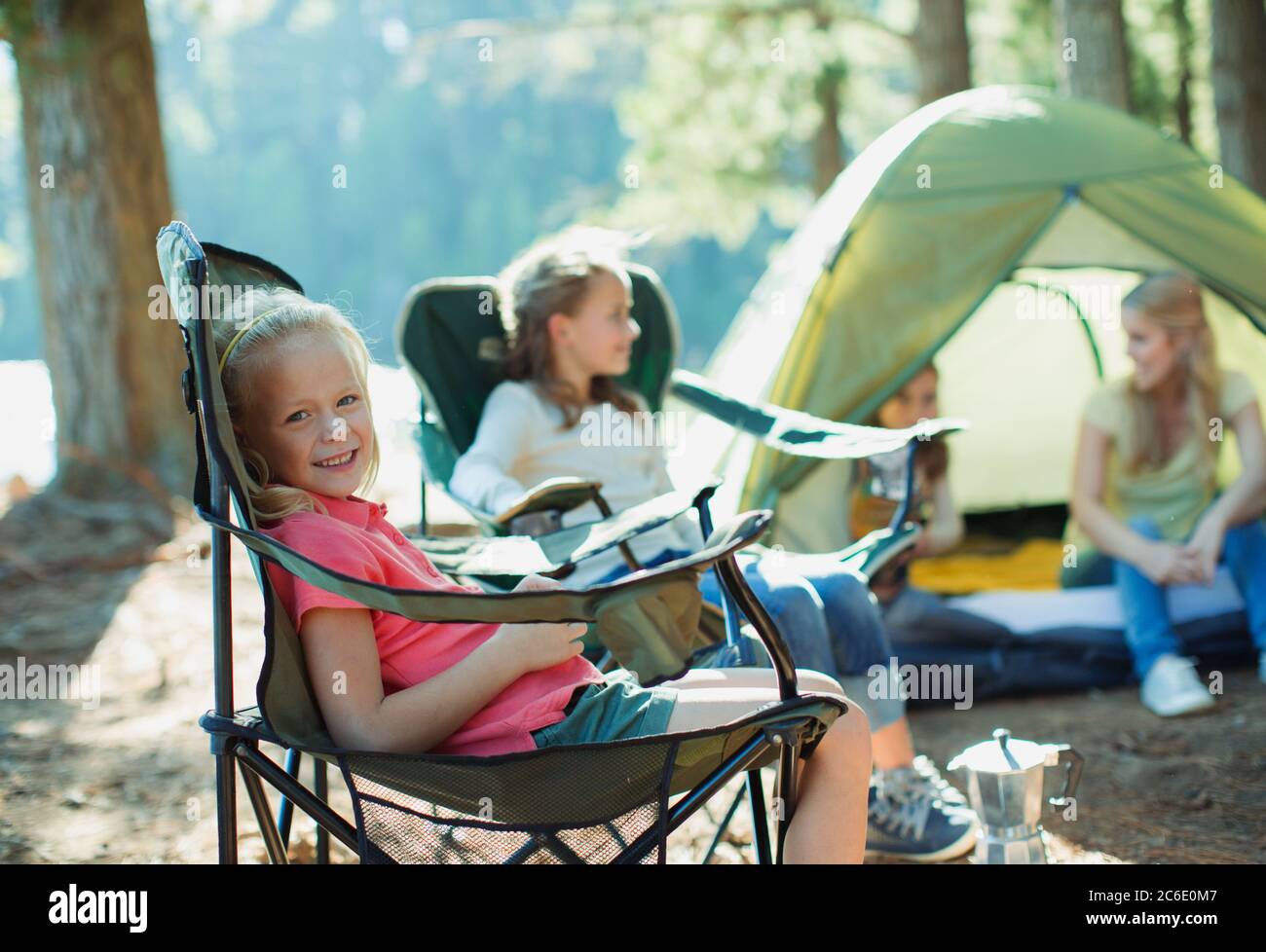 Smiling girl sitting in chair at campsite Stock Photo - Alamy