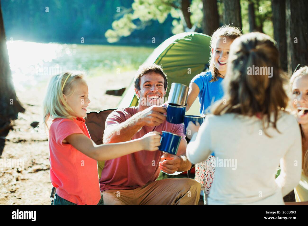 Smiling family toasting mugs at campsite Stock Photo - Alamy