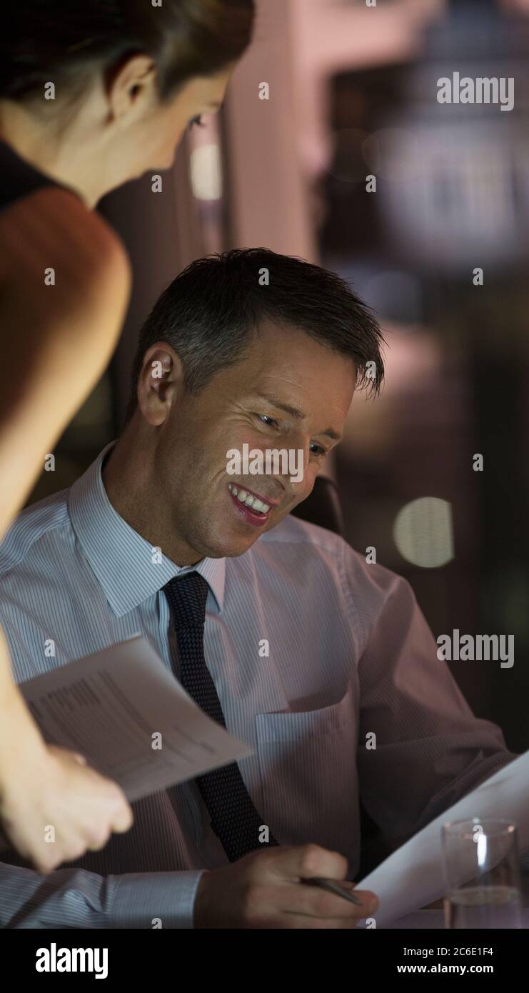 Business people reviewing paperwork in office at night Stock Photo - Alamy
