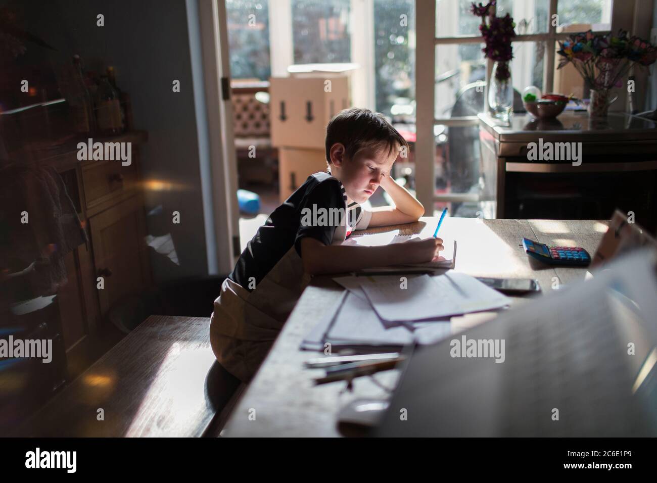 Boy doing homework at dining table Stock Photo - Alamy