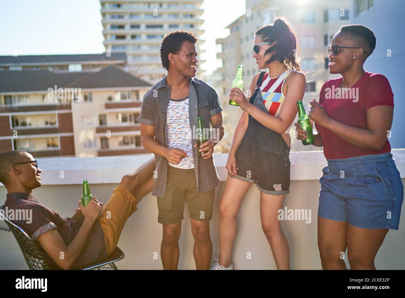 Happy young friends drinking beer on sunny urban rooftop balcony Stock ...
