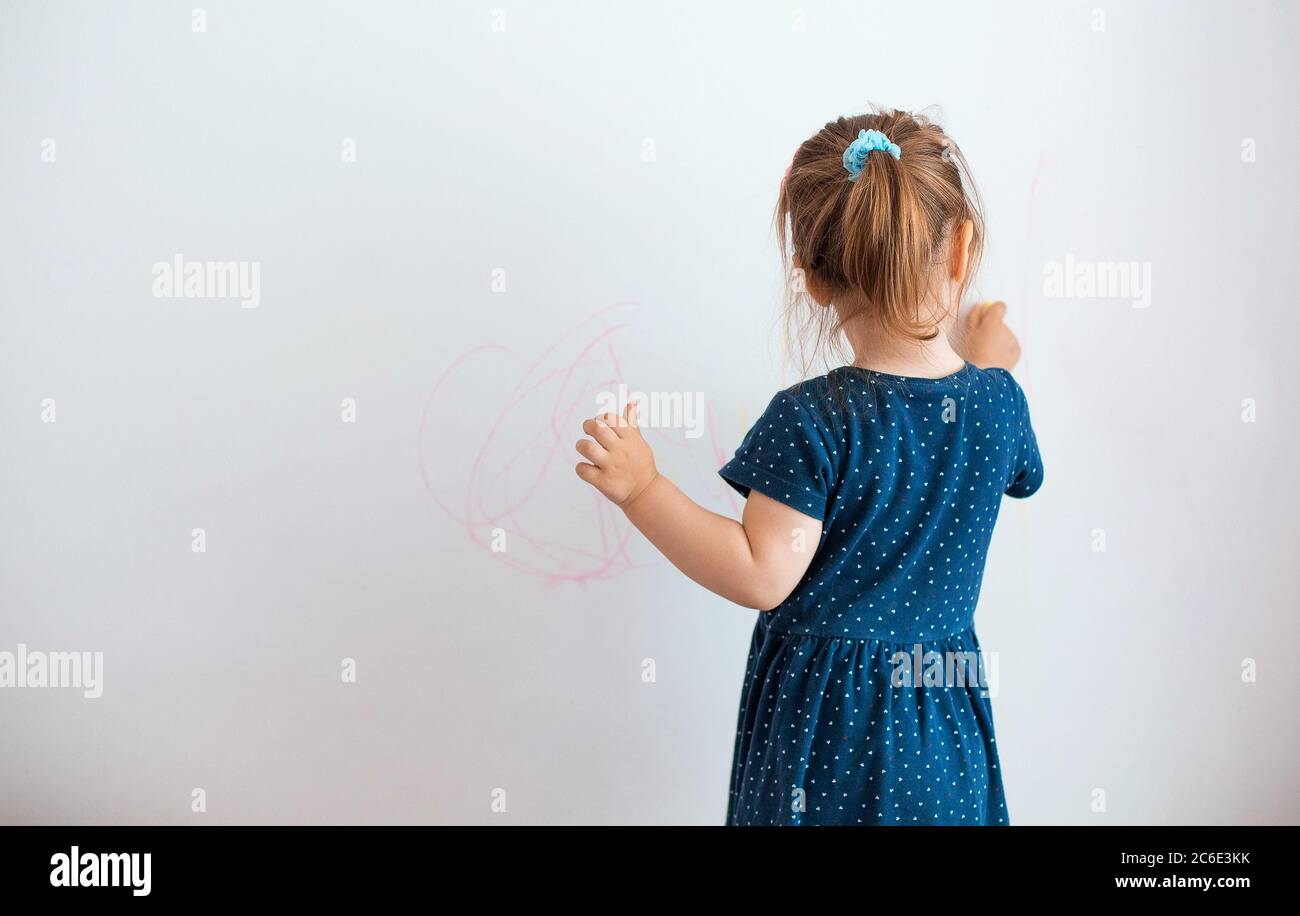 Back view of adorable child in dress standing in modern flat and ...