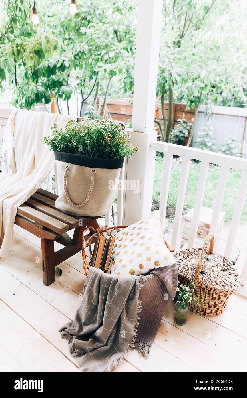 High angle of wooden terrace of house with bench and bunch of flowers ...