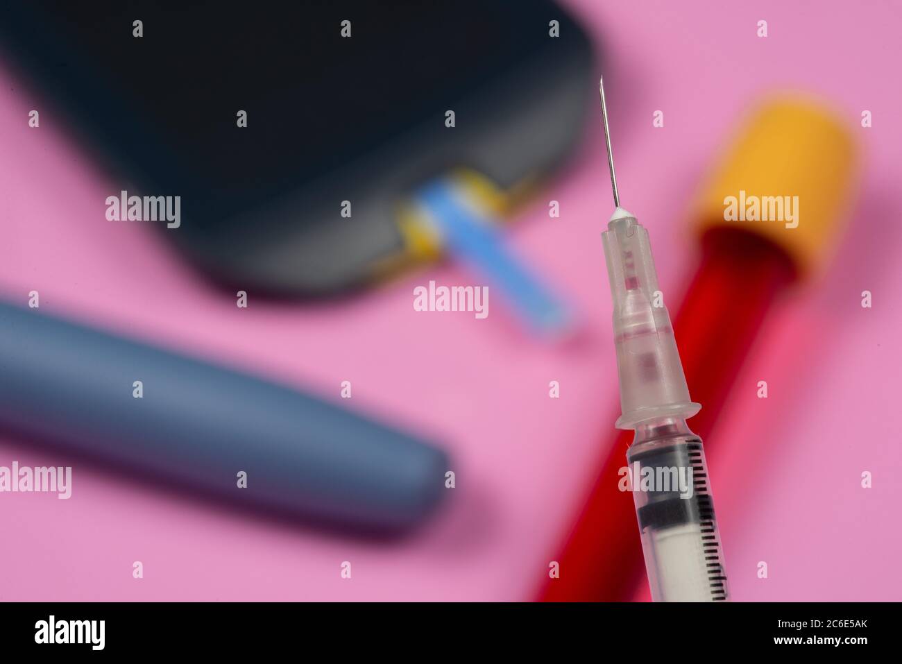 insulin syringe in the foreground, with blurred diabetes objects in the ...