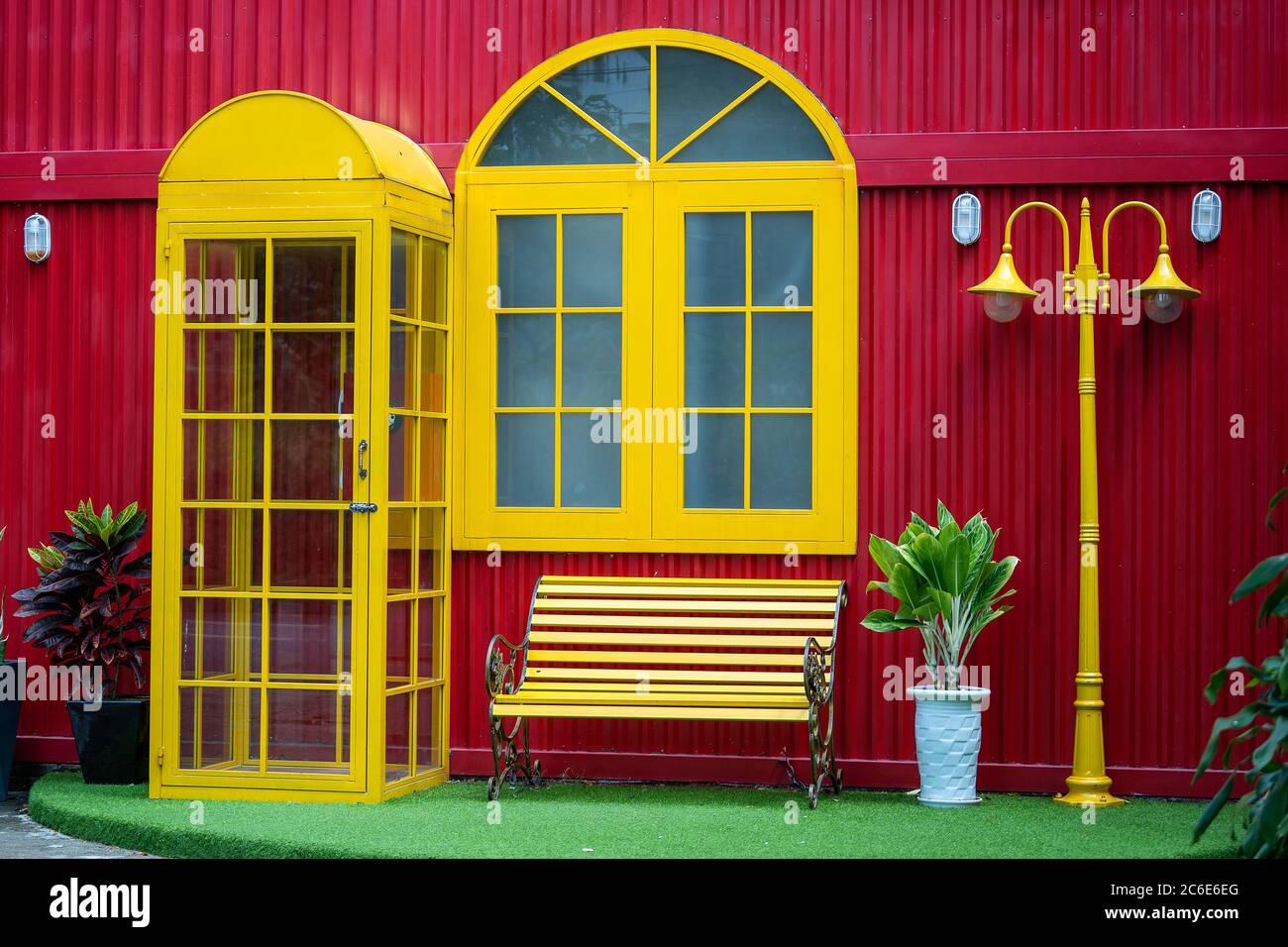 Yellow telephone box, bench and lamppost on the background of a red ...