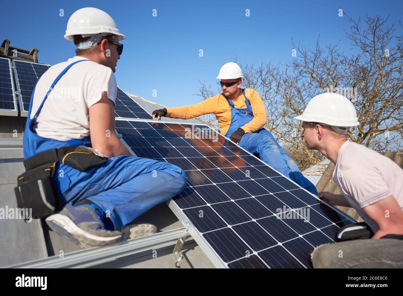Male team workers installing stand-alone solar photovoltaic panel ...