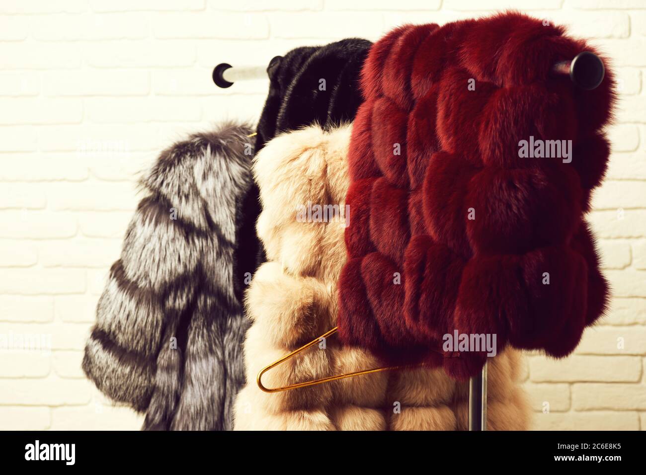 fashionable luxurious waist coats of fur hanging on rack on golden ...