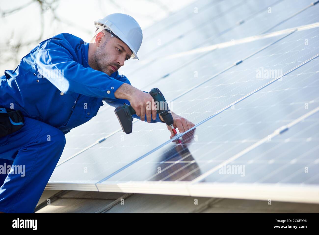 Male engineer in blue suit and protective helmet installing solar ...