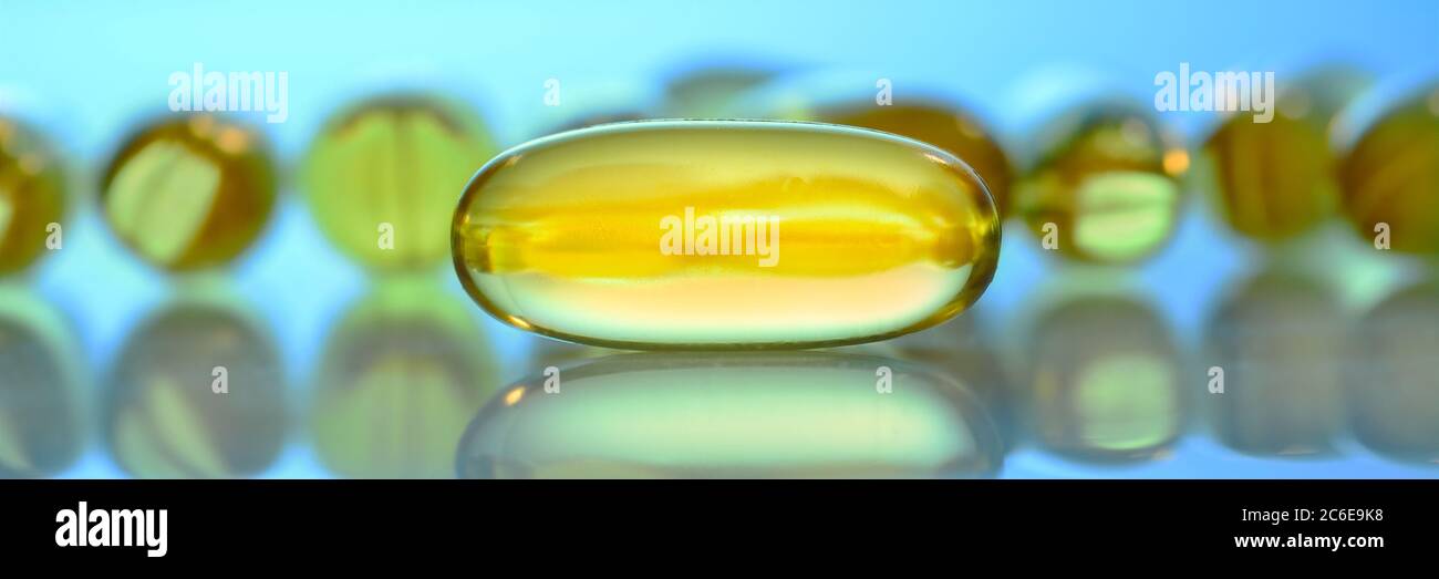 Omega 3 capsule on the gloss blue surface with reflections. Fish oil ...